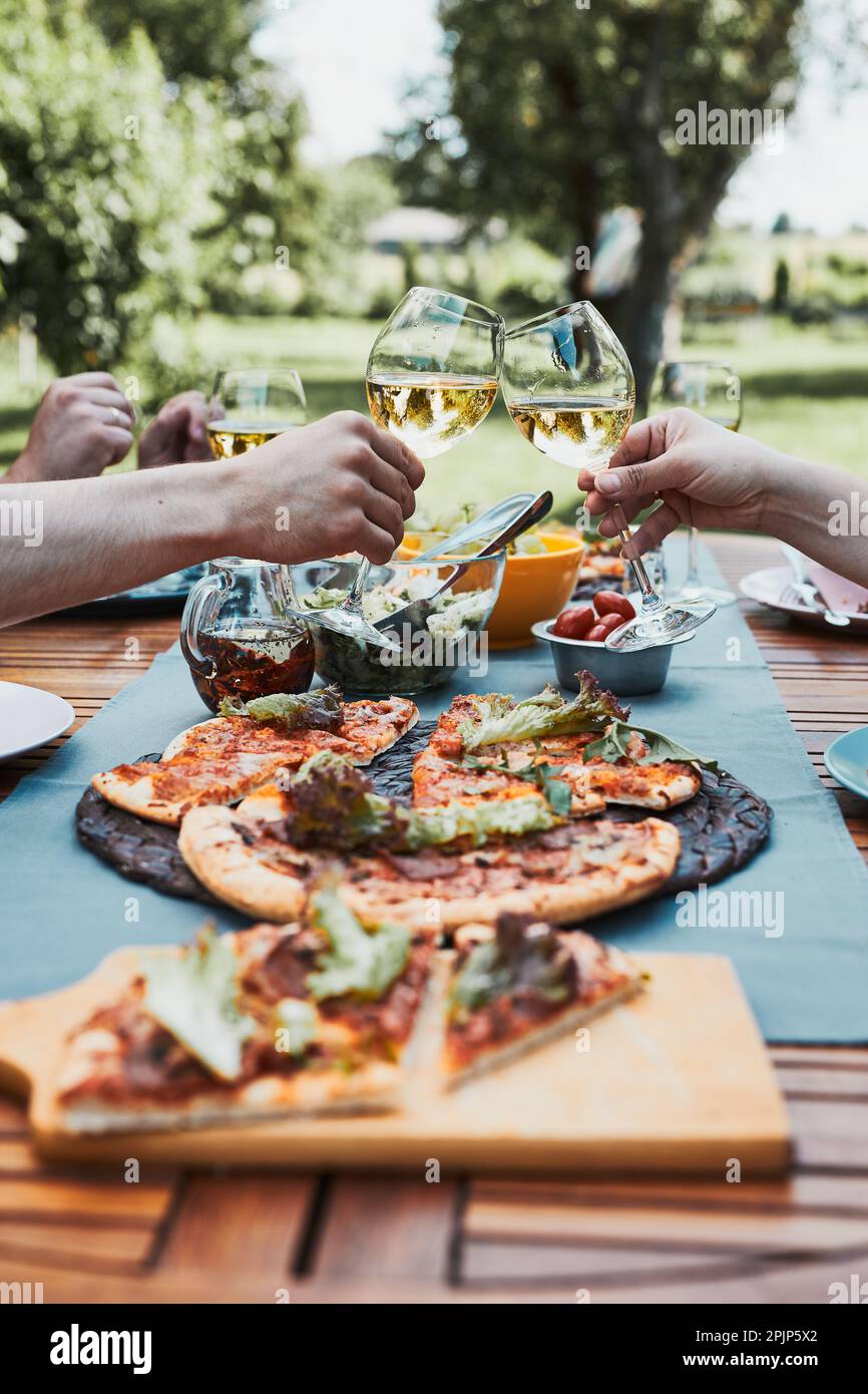 Friends making toast during summer picnic outdoor dinner in a home ...