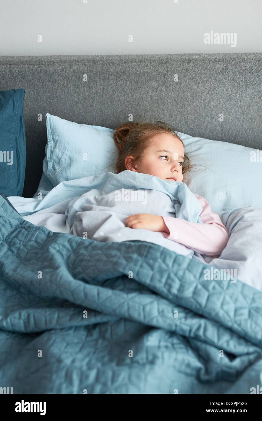 Ill little girl lying in bed covered with duvet. Sick kid recovering ...