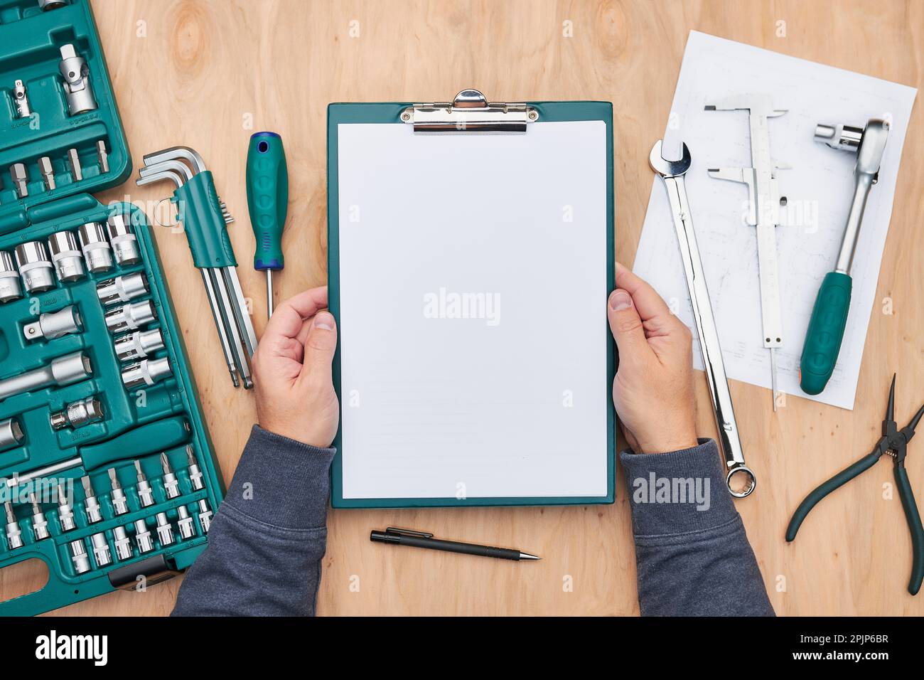 Man working in workshop holding clipboard using many tools. Wrench ...