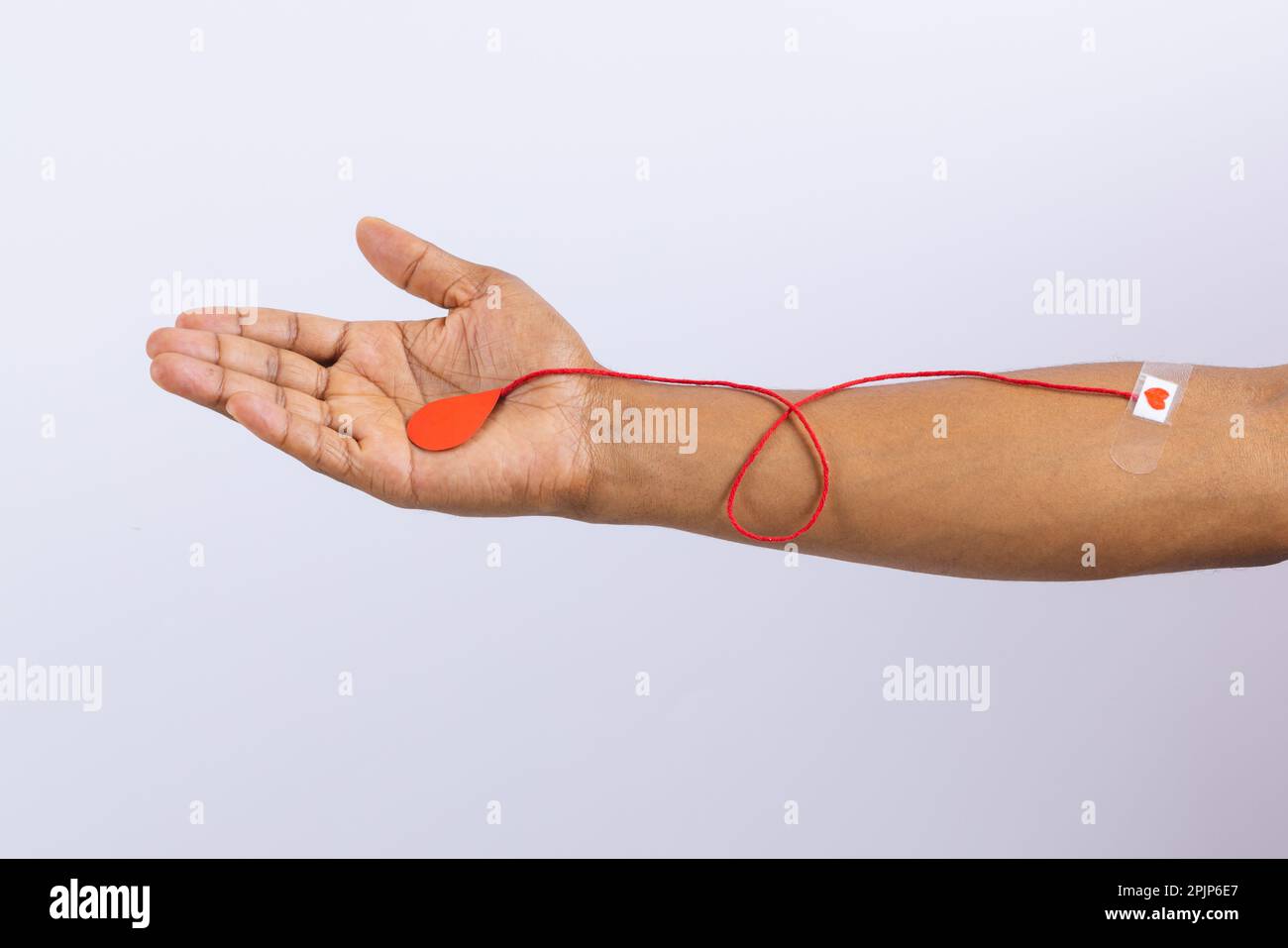 Arm of biracial man with heart sticking plaster and red string with ...