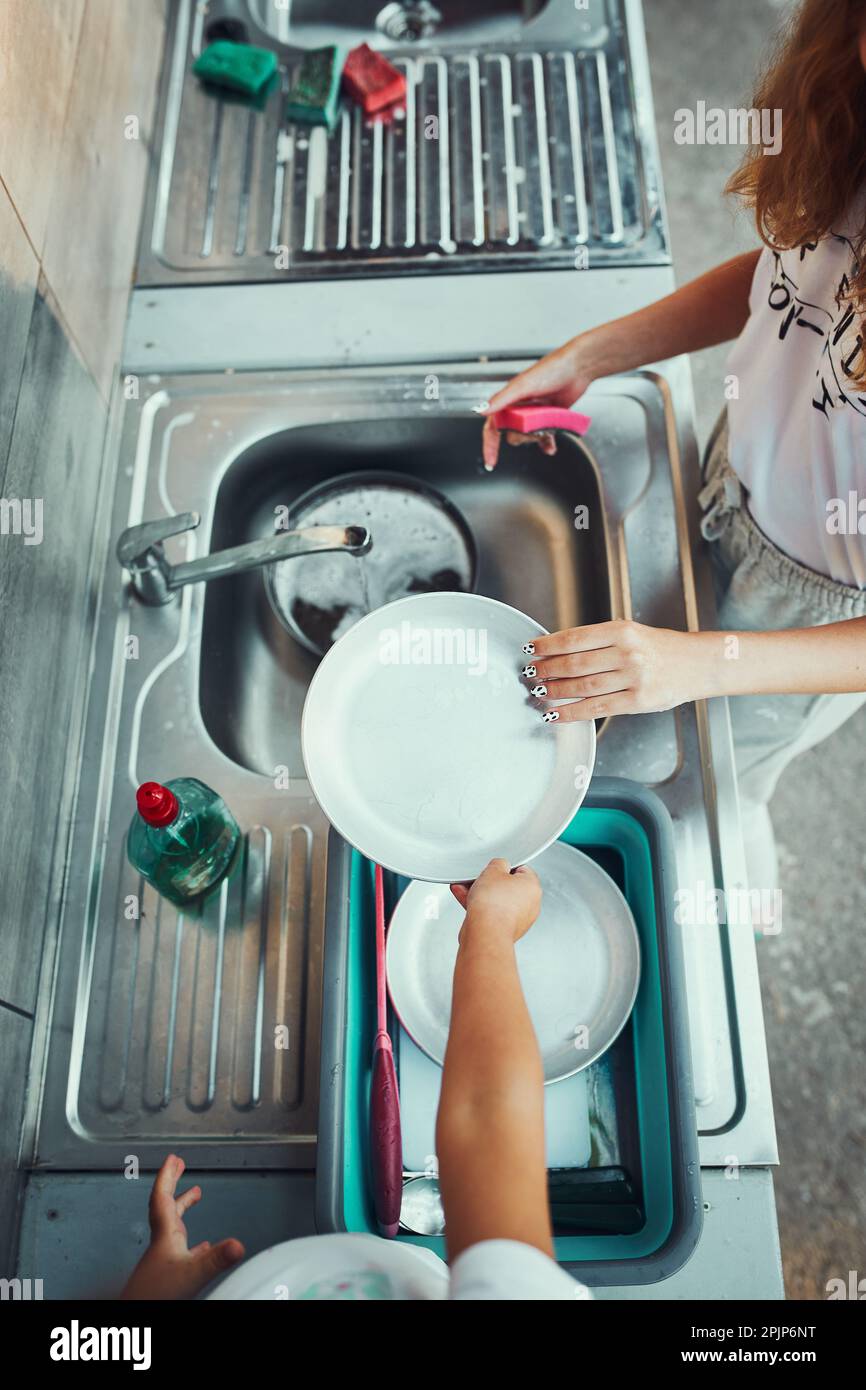 Teenager girl washing up the dishes pots and plates with help her ...