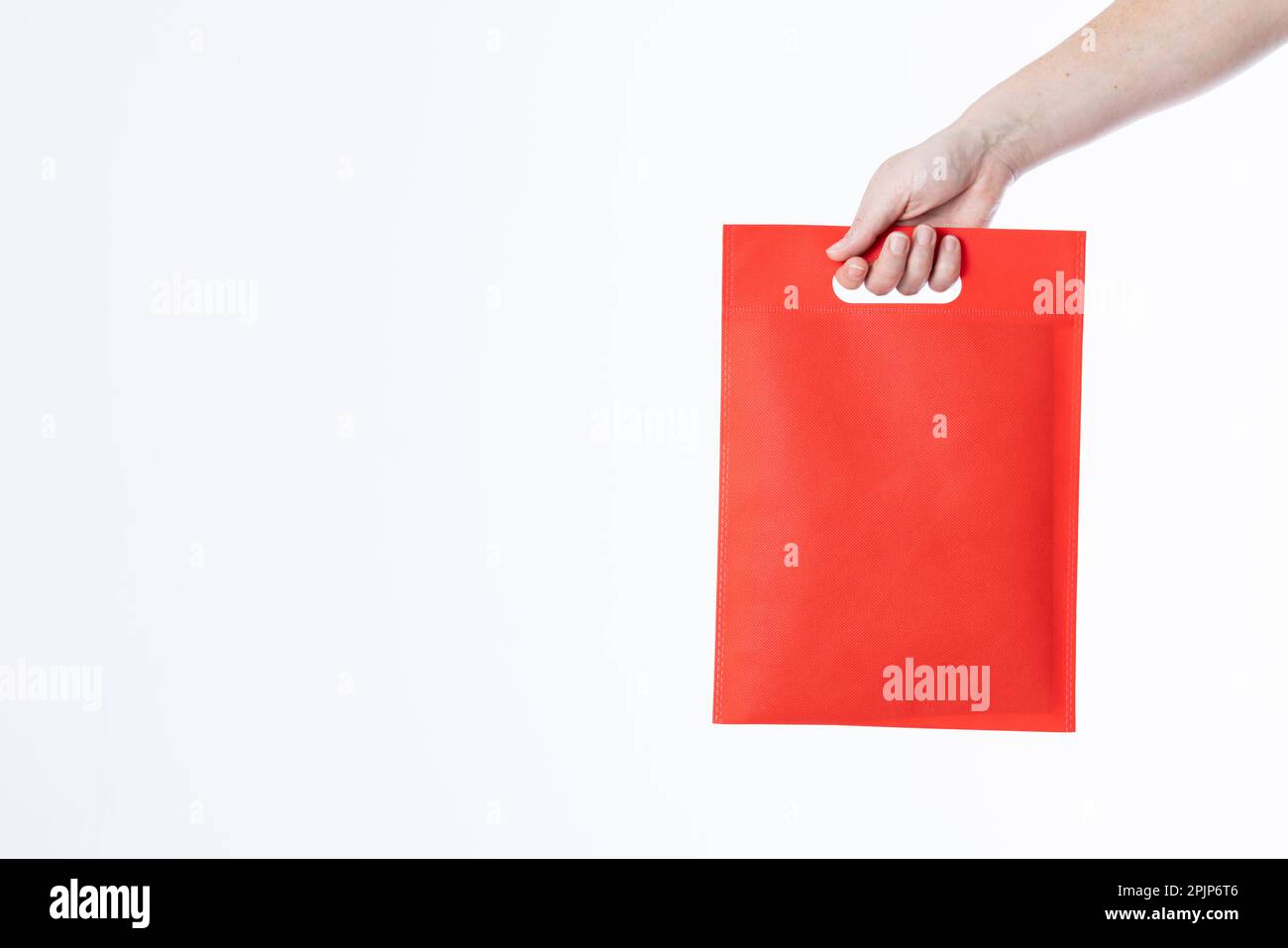 Hand of caucasian woman holding red bag with copy space on white ...