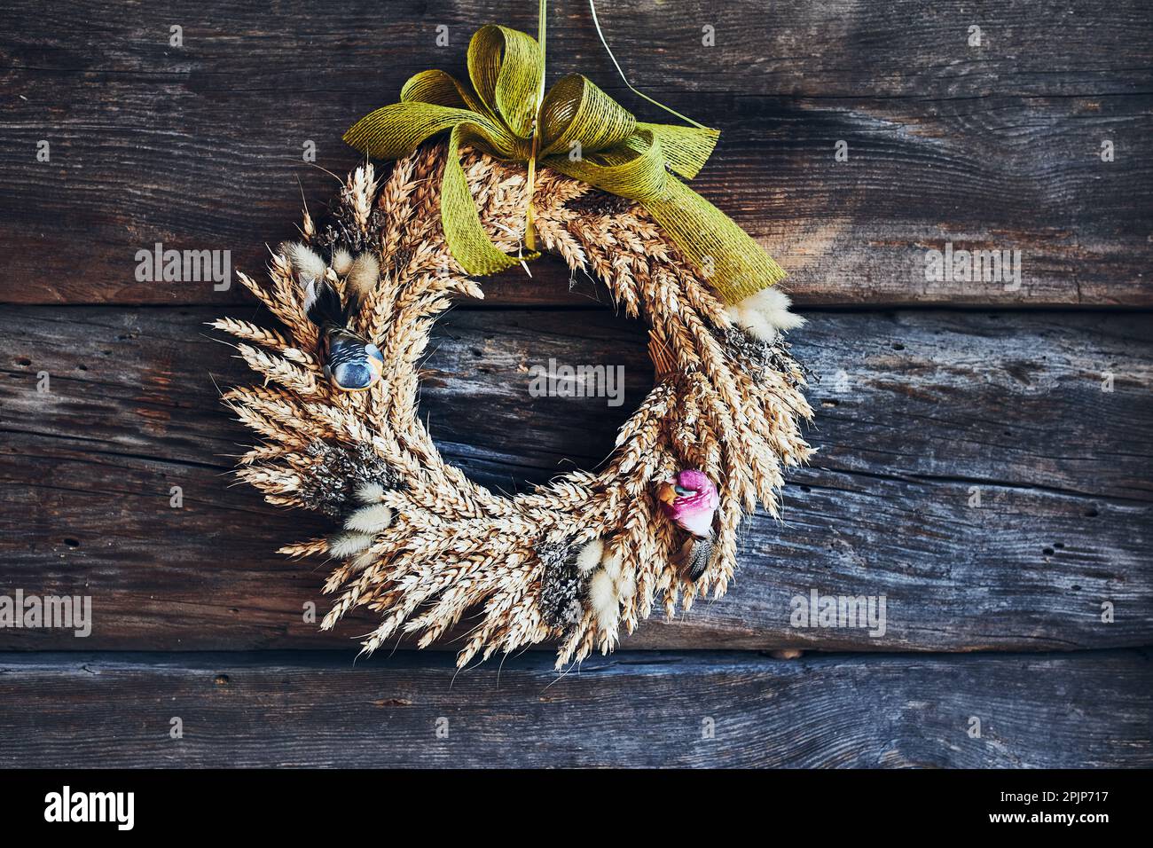 Wreath of golden ears of wheat, dried flowers and herbs tied with red ...
