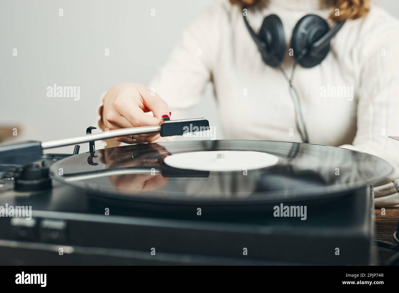 Young woman listening to music from vinyl record player. Playing music ...