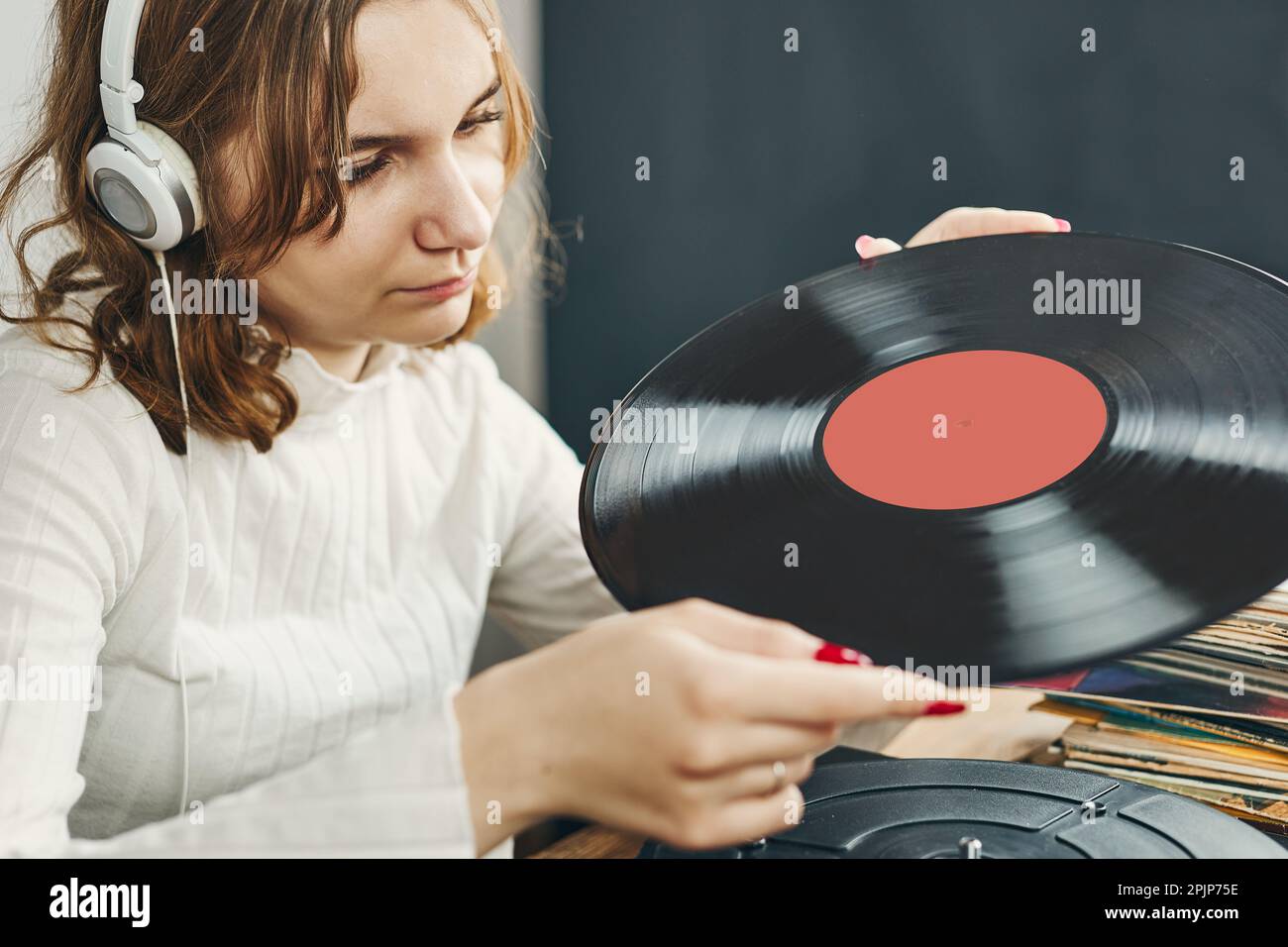 Young woman listening to music from vinyl record player. Playing music ...