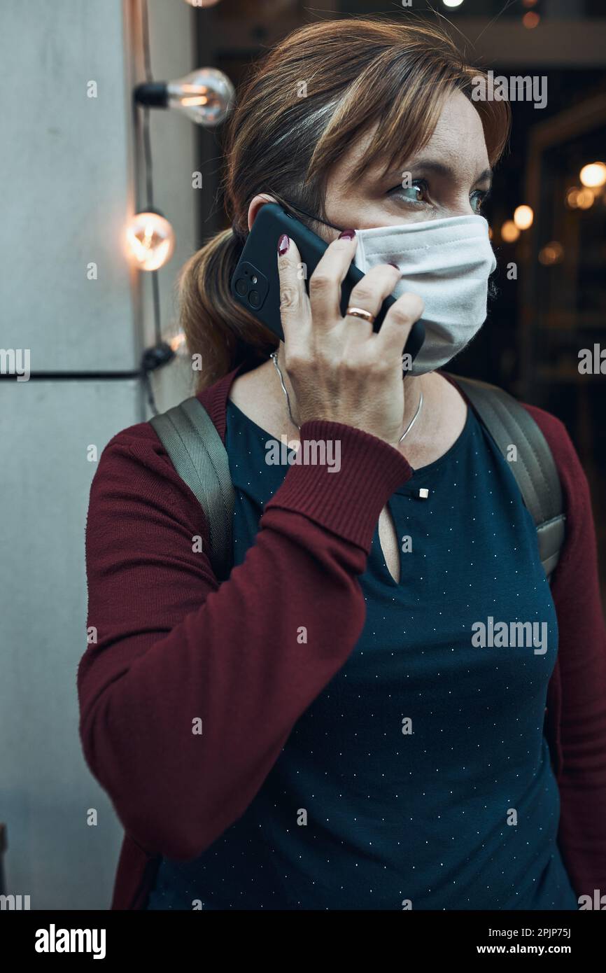 Young woman talking on phone standing in a front of restaurant downtown ...