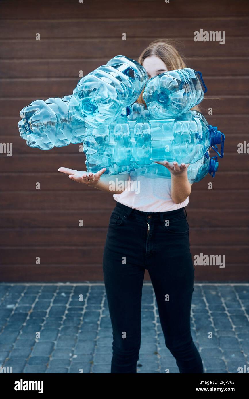 Young woman throwing out empty used plastic water bottles into trash ...
