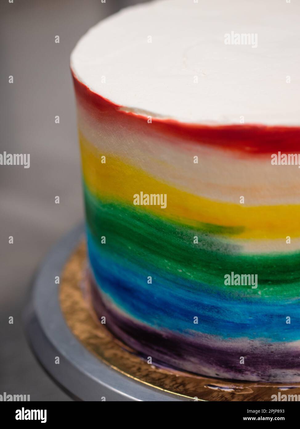 pastry chef working on a frosted cup cake with lgbt rainbow colours for ...