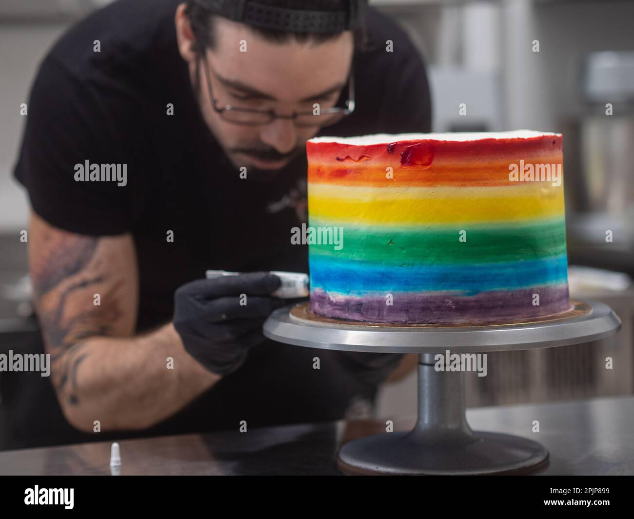 pastry chef working on a frosted cup cake with lgbt rainbow colours for ...