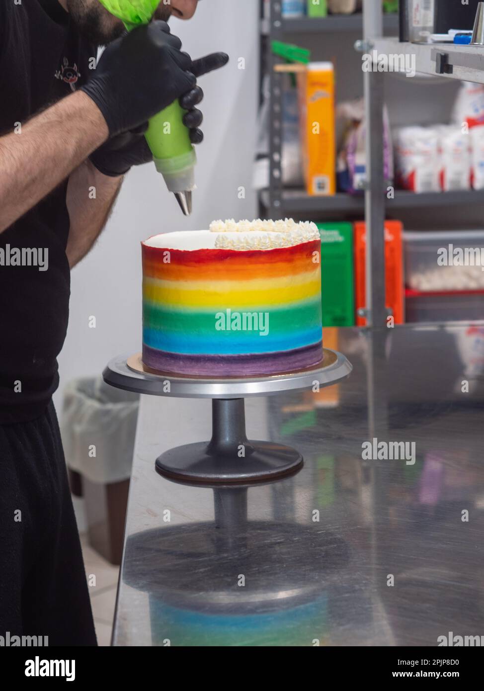 pastry chef working on a frosted cup cake with lgbt rainbow colours for ...