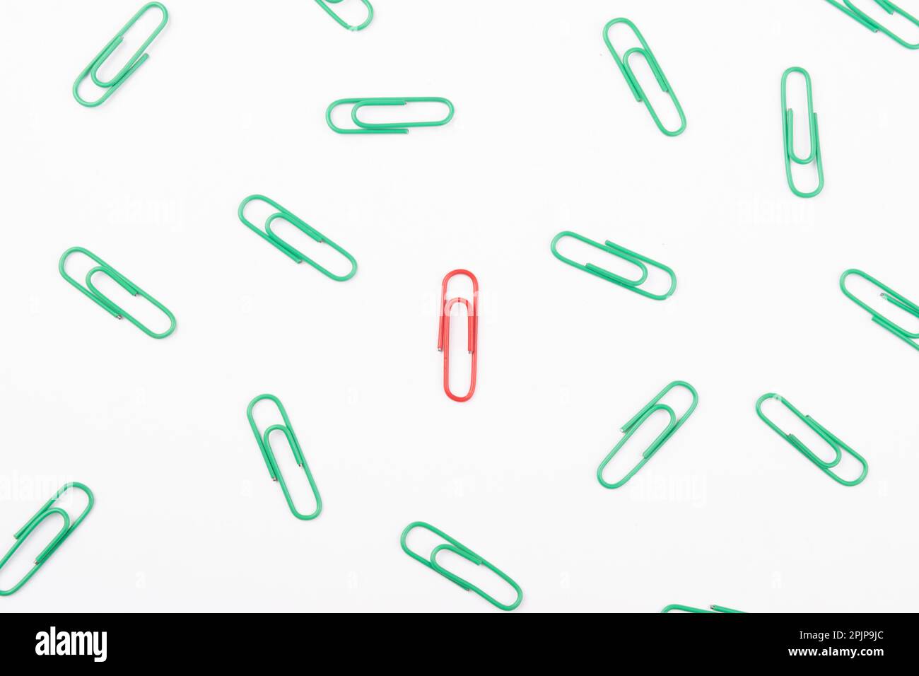 Red paperclip and multiple green paperclip on white background, unique ...
