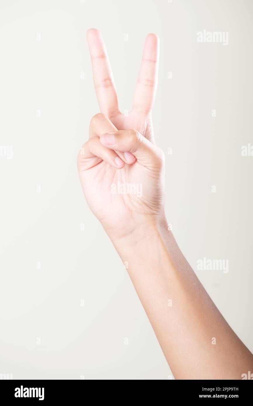 Victory hand gesture on grey background Stock Photo - Alamy