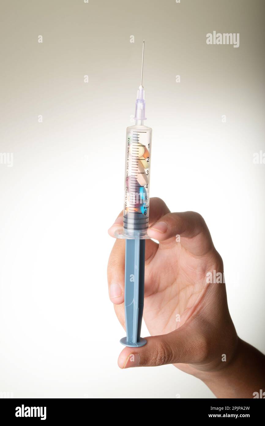 Hand holding injection with pills on grey background Stock Photo - Alamy