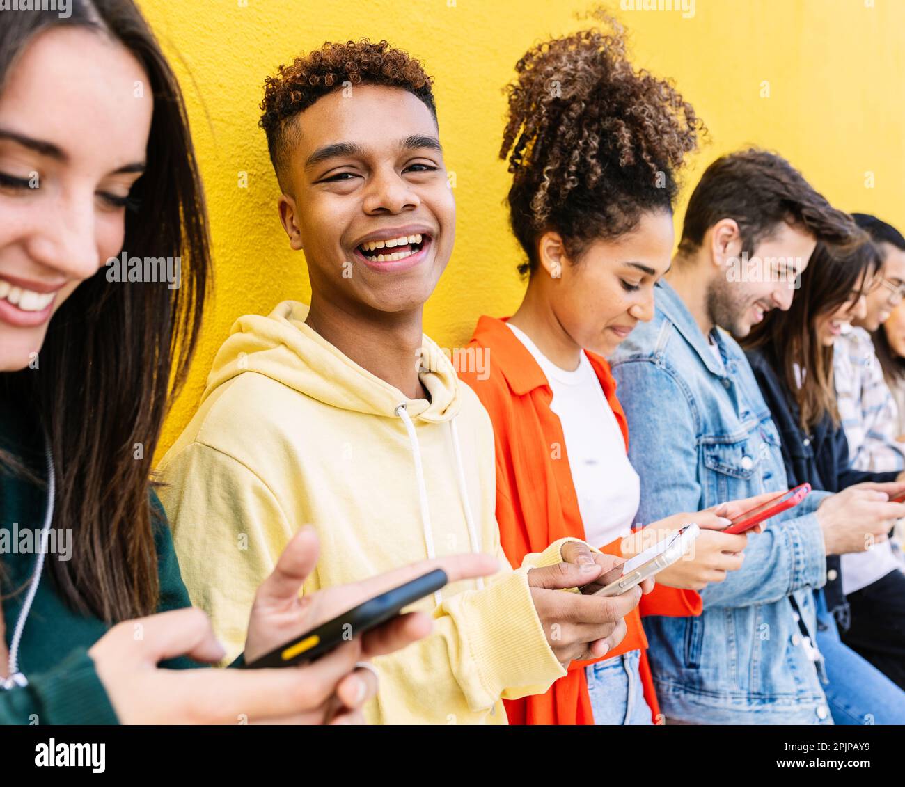 Teenage young people using mobile phone over yellow background Stock ...