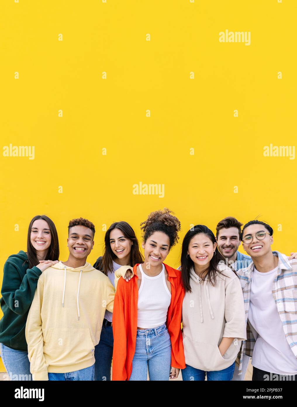 Happy young group of teenage people smiling at camera over yellow ...
