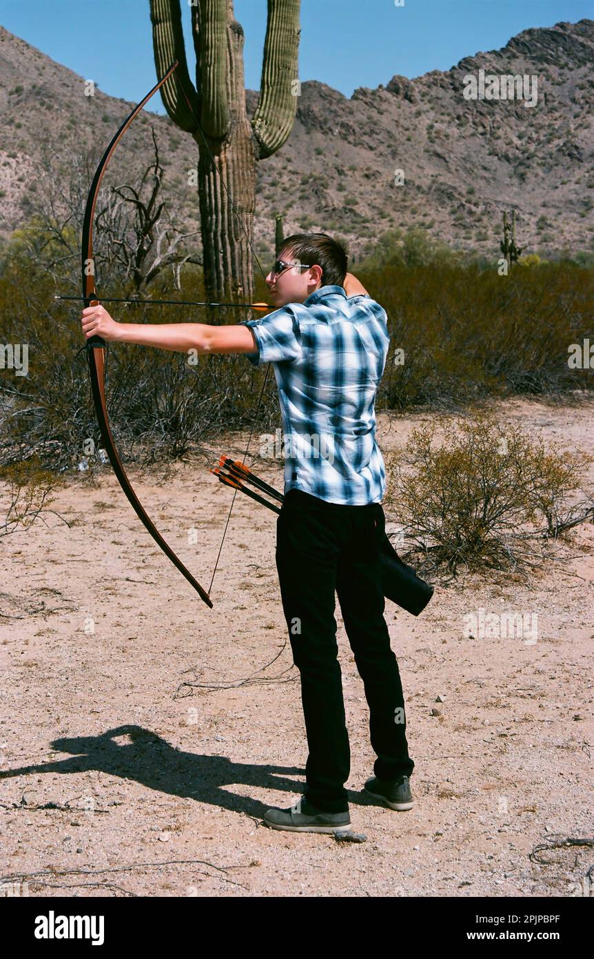 Young man shooting a bow and arrow in the desert Stock Photo - Alamy
