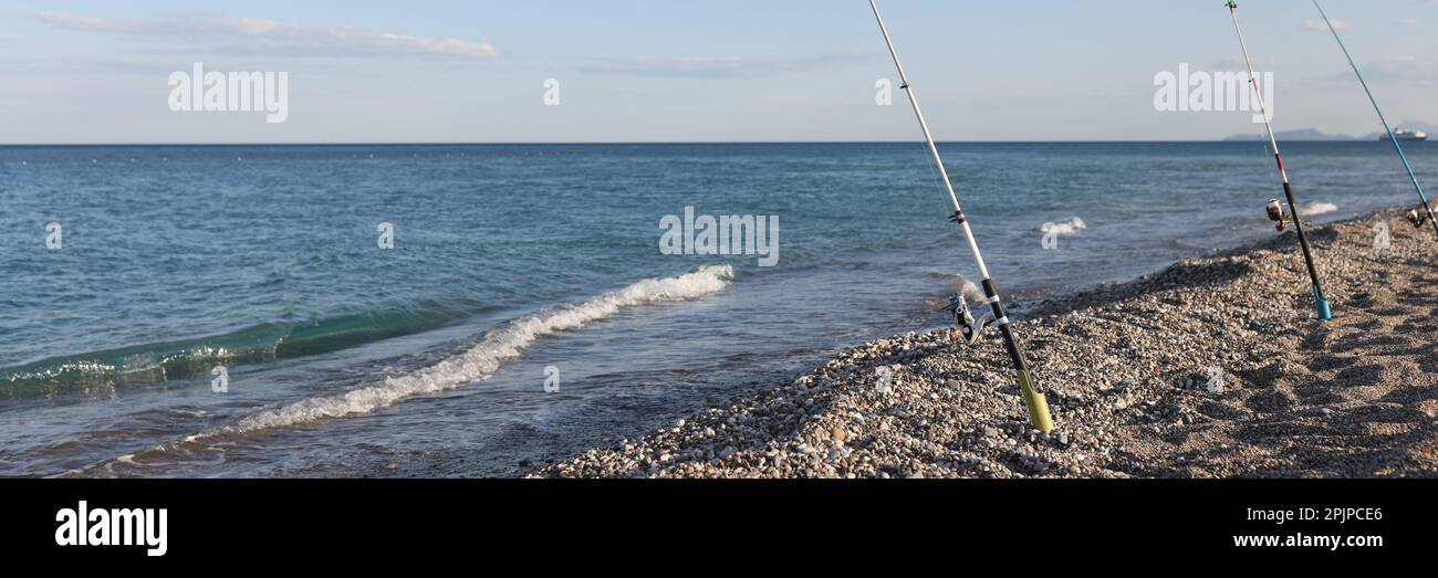 Fishing rods on sandy beach along sea Stock Photo - Alamy