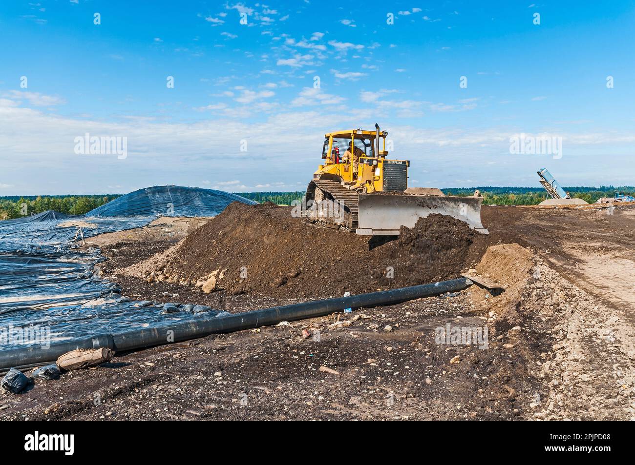 A soil compactor bulldozer tractor moves (contours) dirt around in an ...
