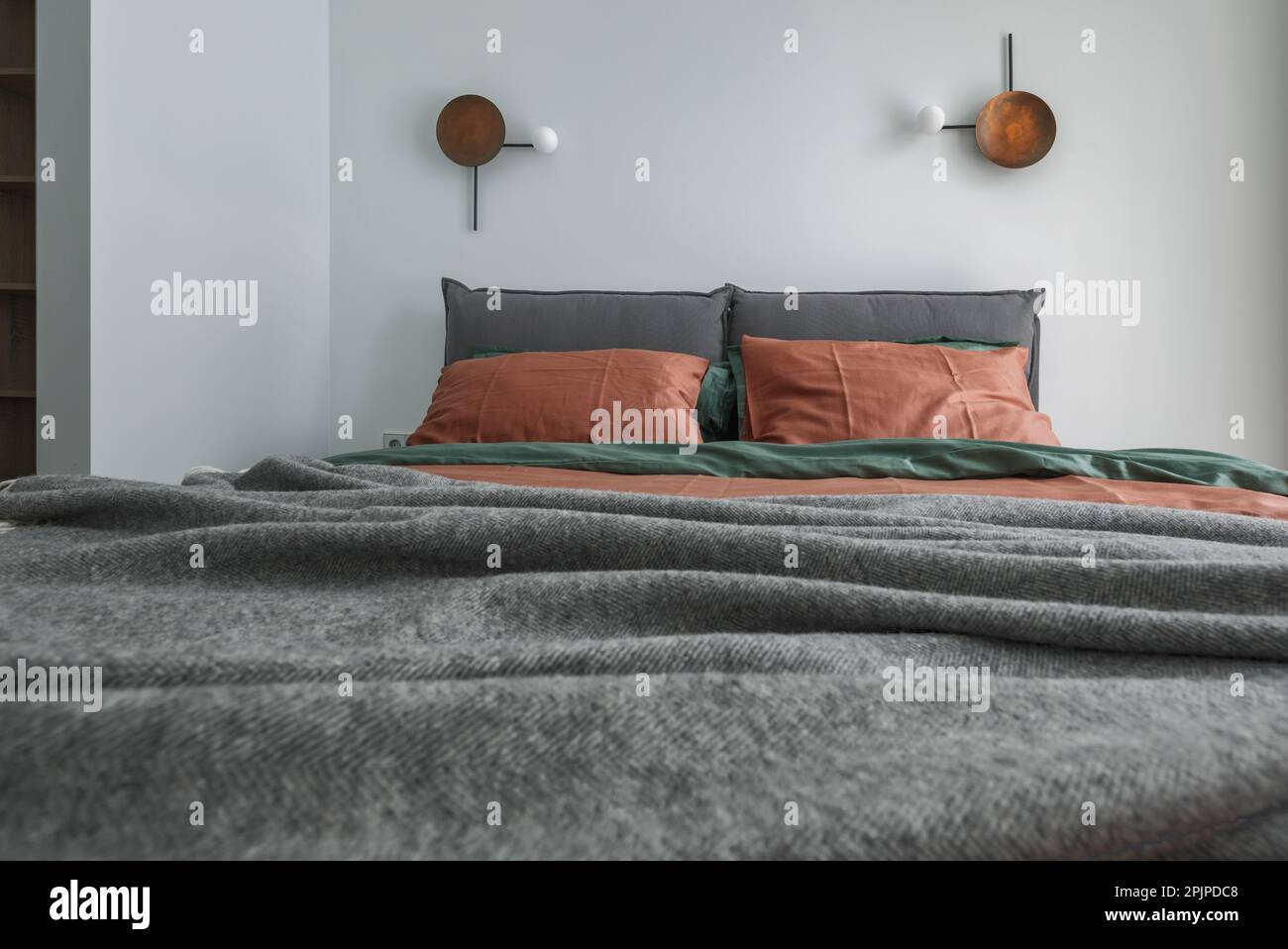 Bedroom interior with rust color linen and cushions on a bed, grey ...