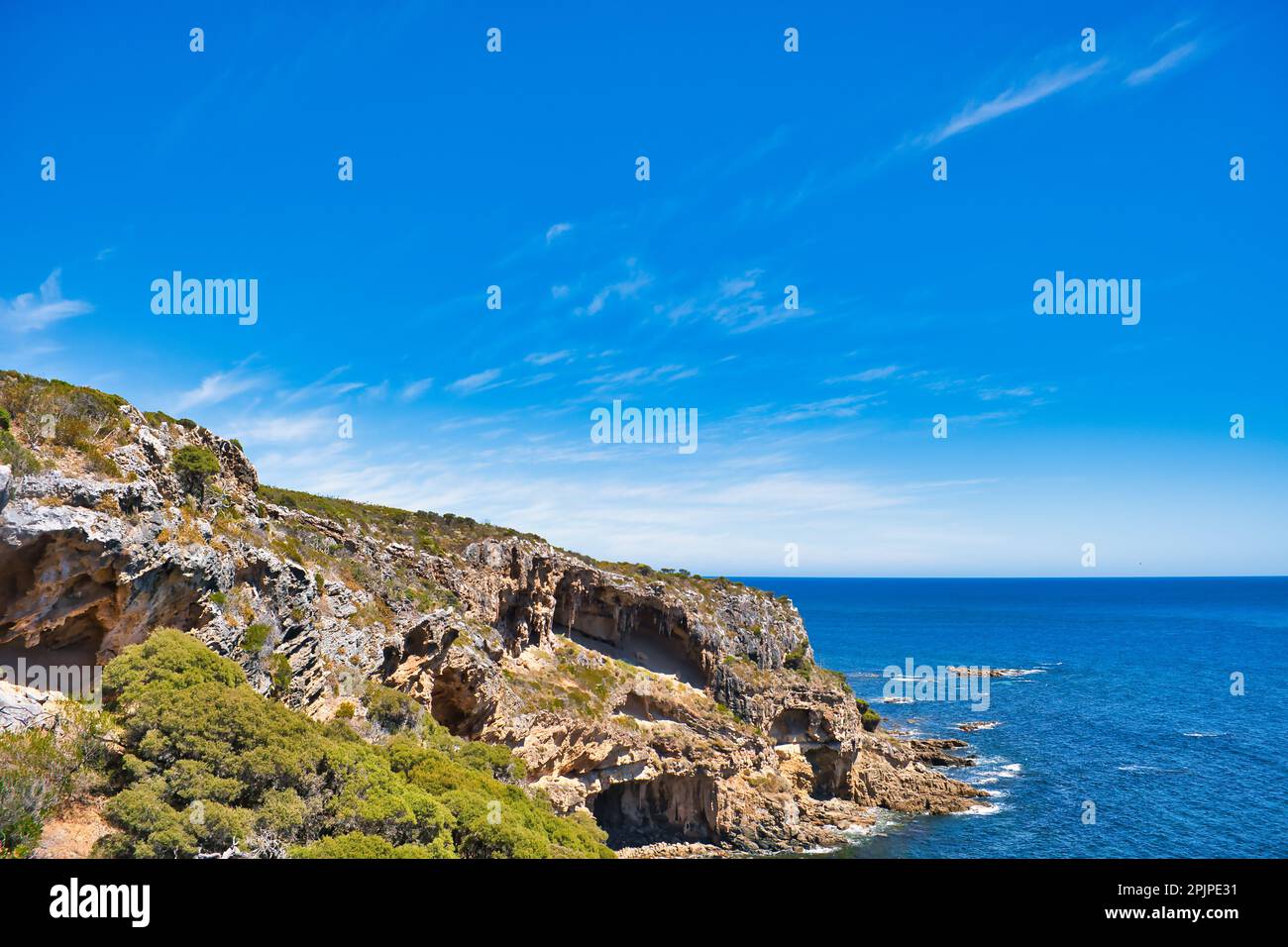 Craggy limestone cliffs with caves at the coast of Cape Naturaliste, at ...