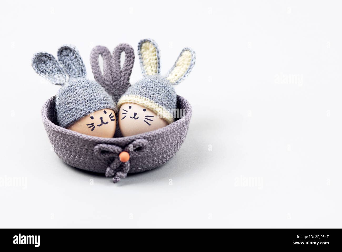 Two Easter eggs with funny faces and gray crocheted hats with bunny ...