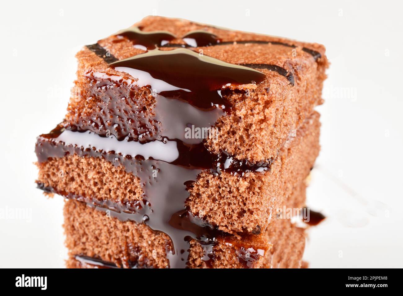 Piece of chocolate cake dripping with chocolate syrup isolated on white ...