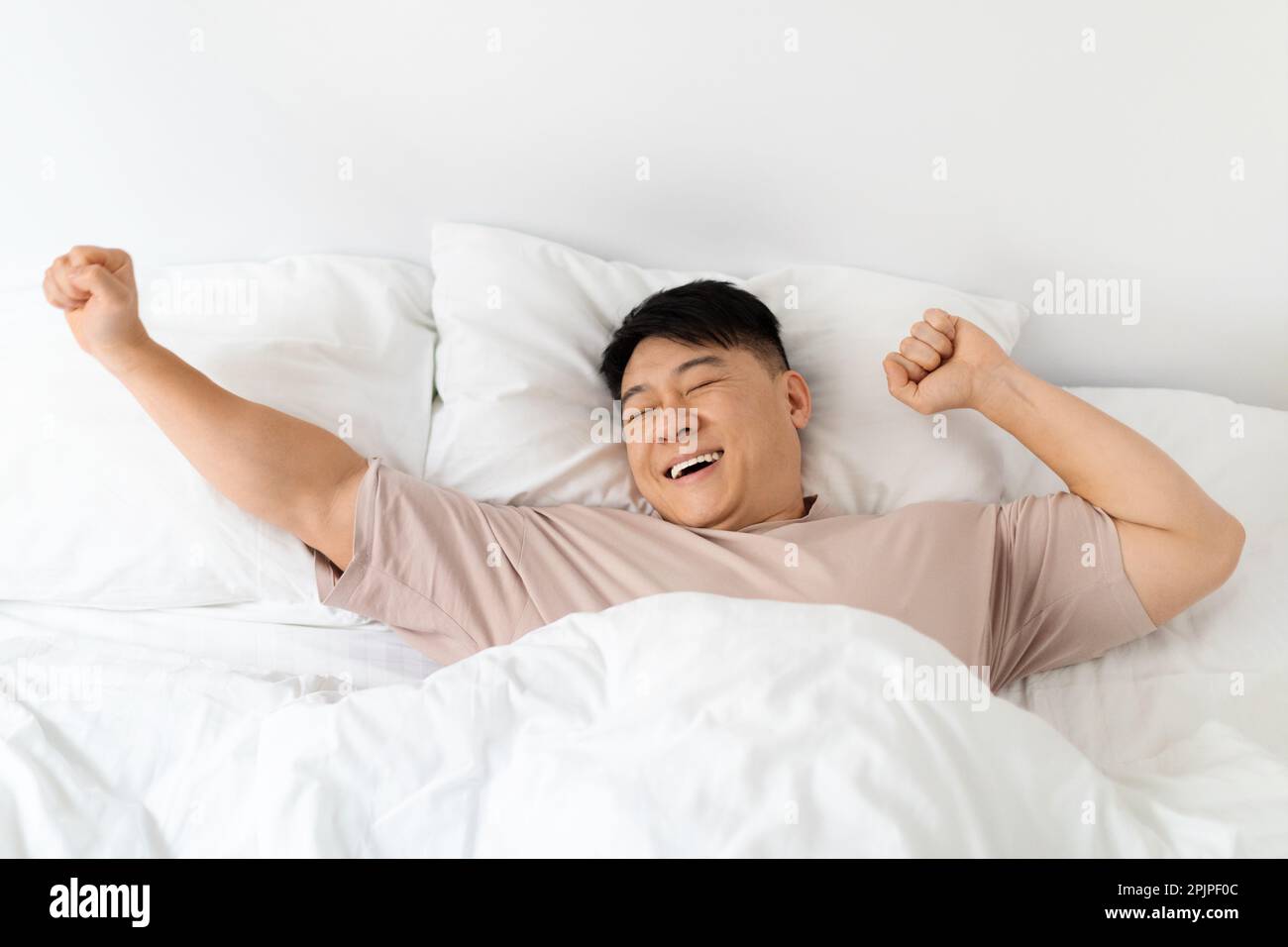 Top view of smiling asian man stretching in bed Stock Photo - Alamy