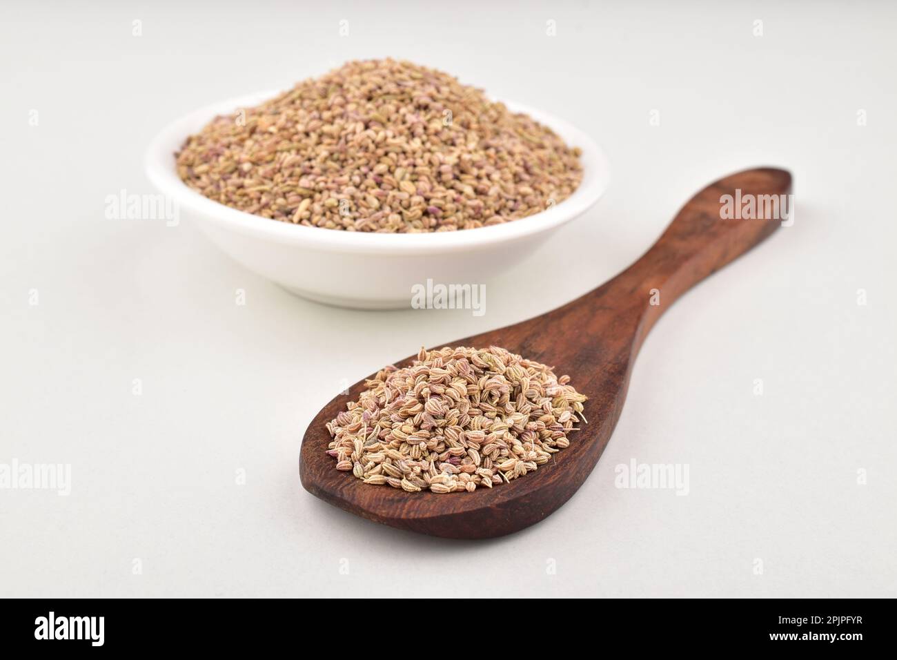 Closeup of carom seeds in spoon and bowl on white background Stock ...