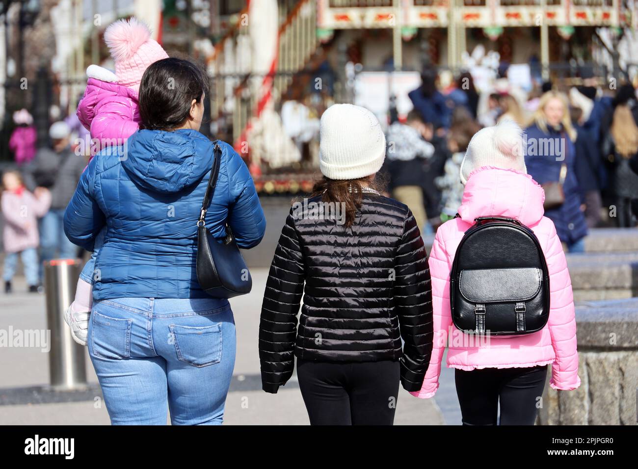 Woman with three children walking on a street in crowd of people ...