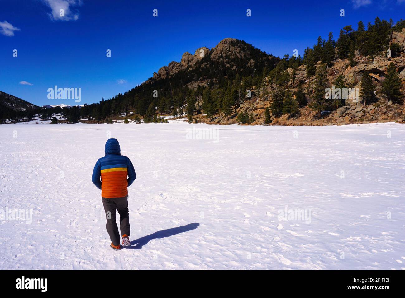 Man walking on frozen lake, Rocky Mountains National Park, Colorado ...