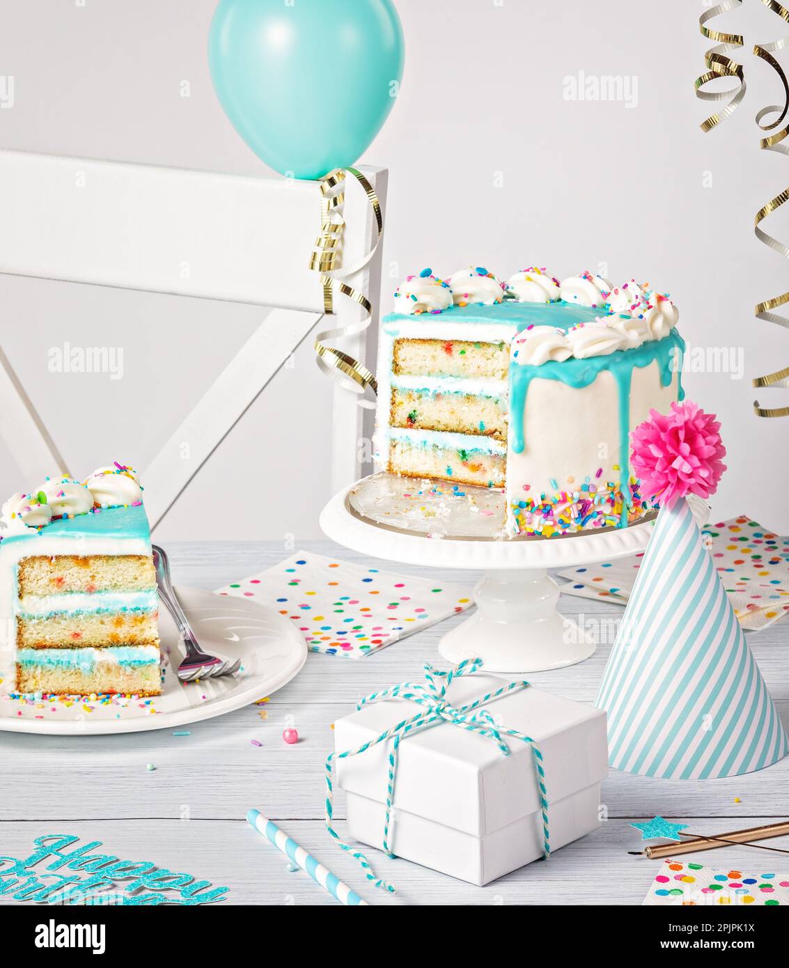 Birthday party table setting with a teal blue ganache drip cake on a ...