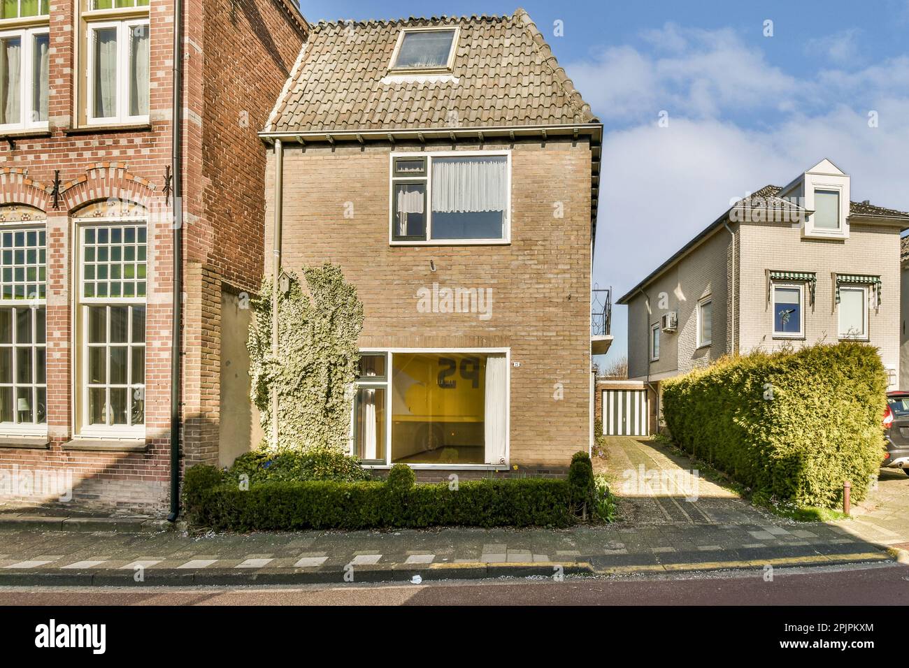 a house in the middle of a street with cars parked on both sides and ...