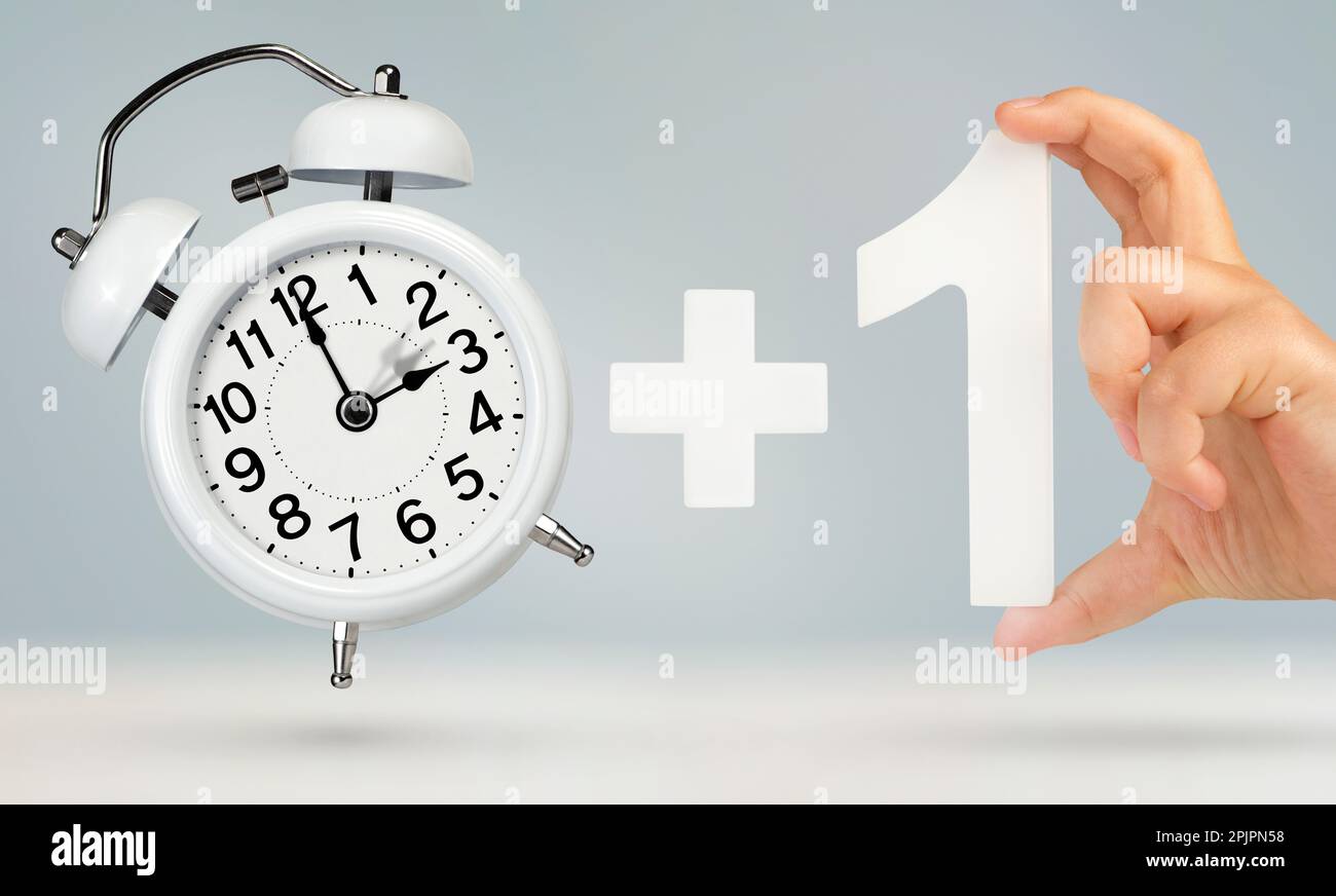 Change time. Spring forward, on a gray background. A white alarm clock ...