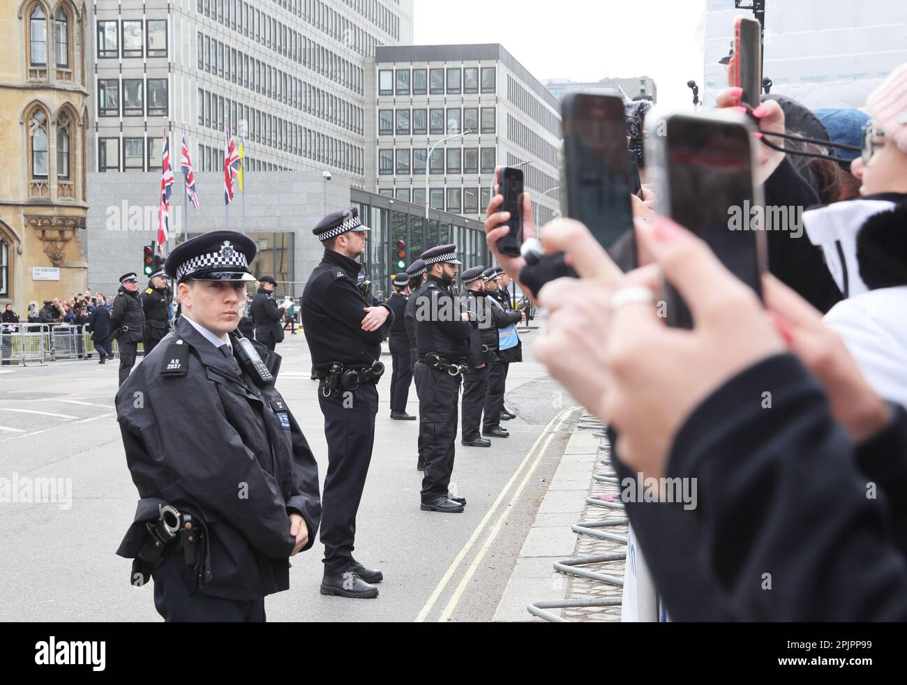 Police line the route and people wait with their mobile phones, outside ...