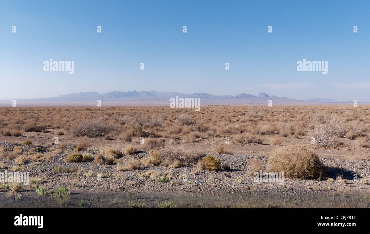 An arid landscape with a vast expanse of barren desert terrain and a ...
