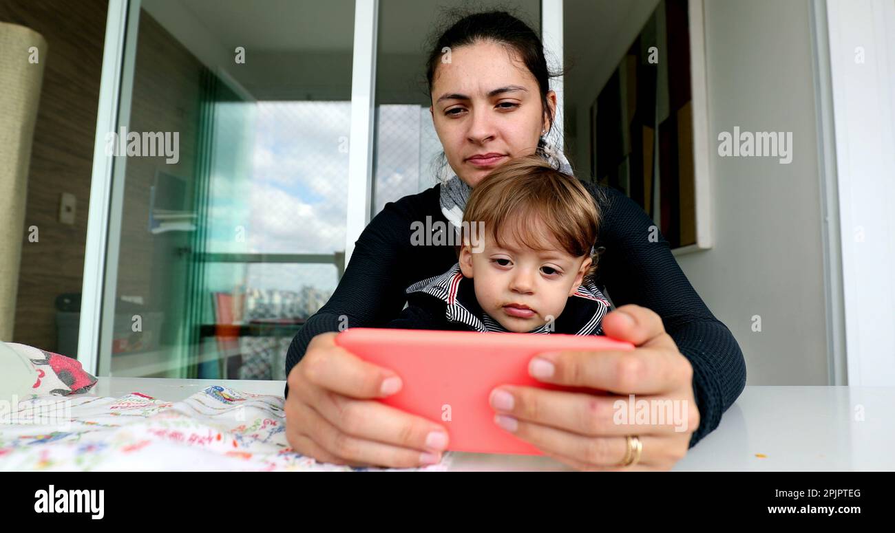 Mother and toddler watching online content on cellphone. Parent and ...
