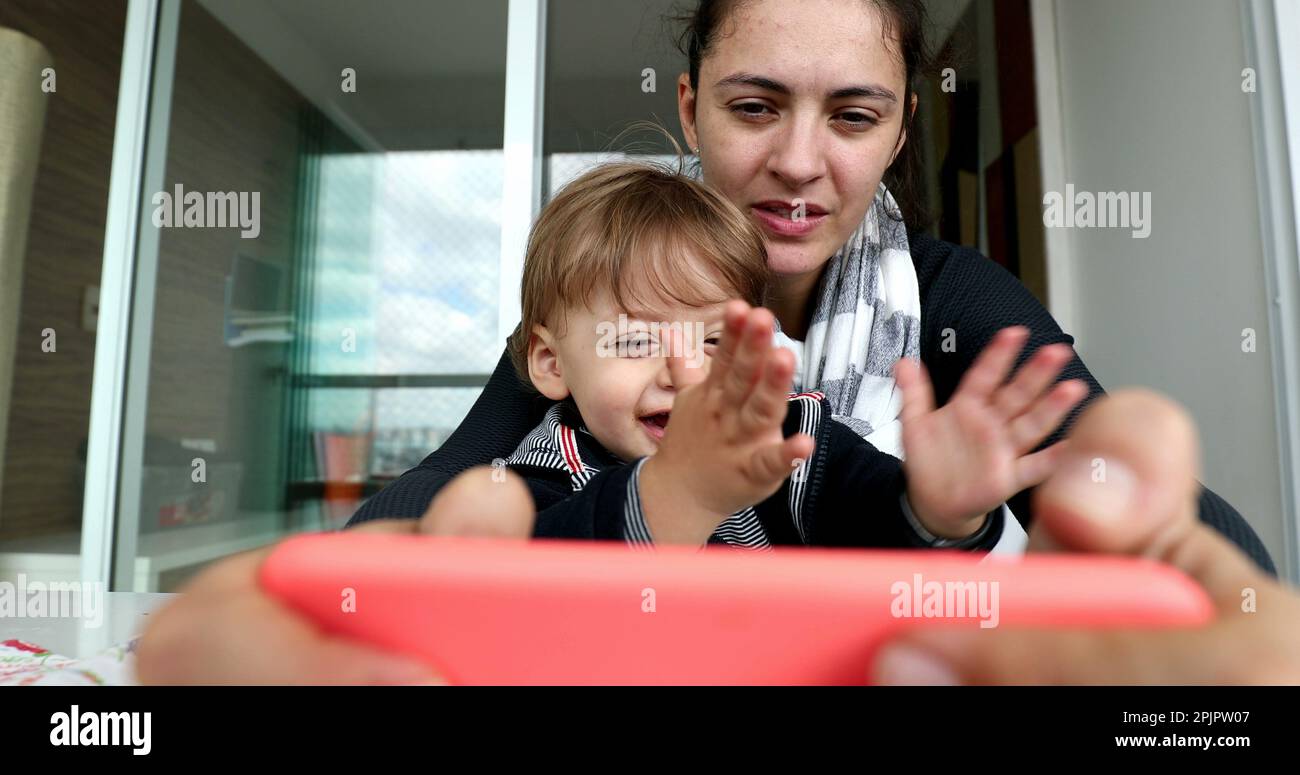 Happy baby toddler on mother lap watching content on cellphone. Child ...