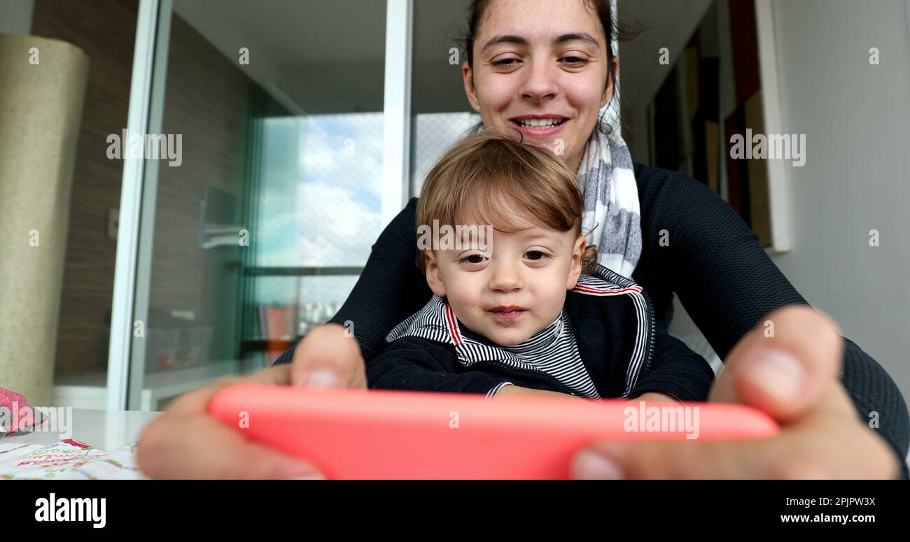 Happy baby watching cellphone screen with mom. Close-up mother holding ...