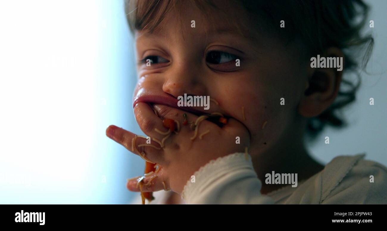 Messy baby eating with hand. Cute dirty infant child boy eats noodle ...