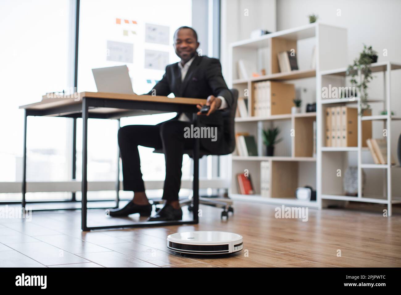 Remote-controlled robotic vacuum removing dust from laminate wooden ...