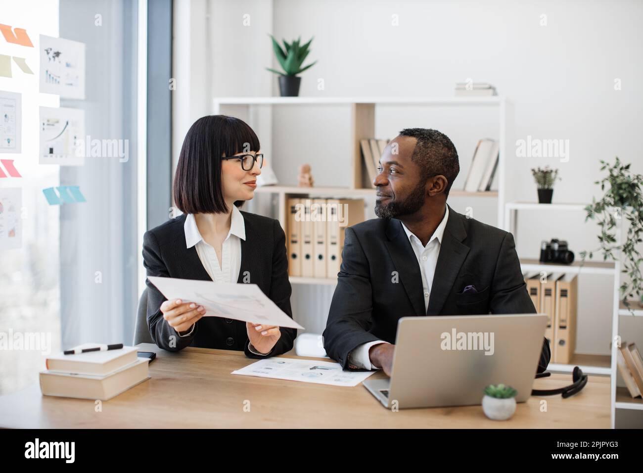 Caucasian bespectacled woman and bearded multiracial man reviewing ...