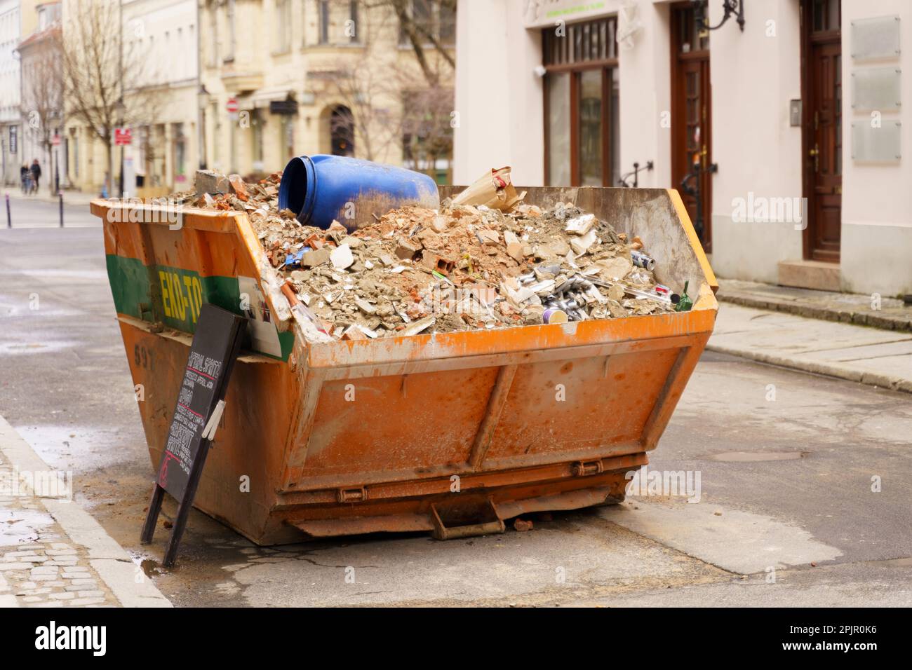 The yellow metal bin is filled with building debris and is ready to be ...