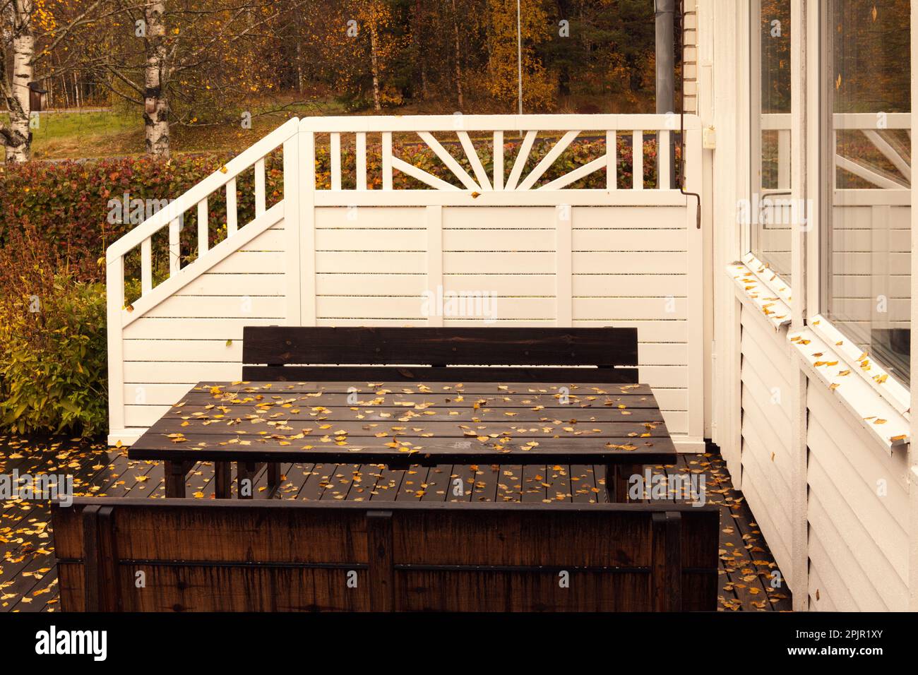 View through a window into an autumn-wet balcony. Leaves, furniture ...