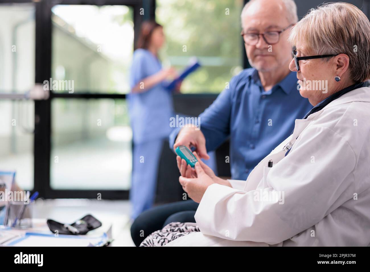 Senior medic taking patient insulin level test using glucometer in ...