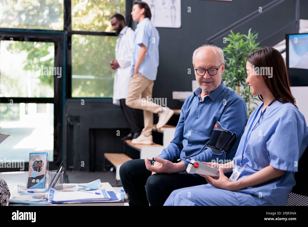 Asian medical assistant measuring hypertension on tonometer in hospital ...