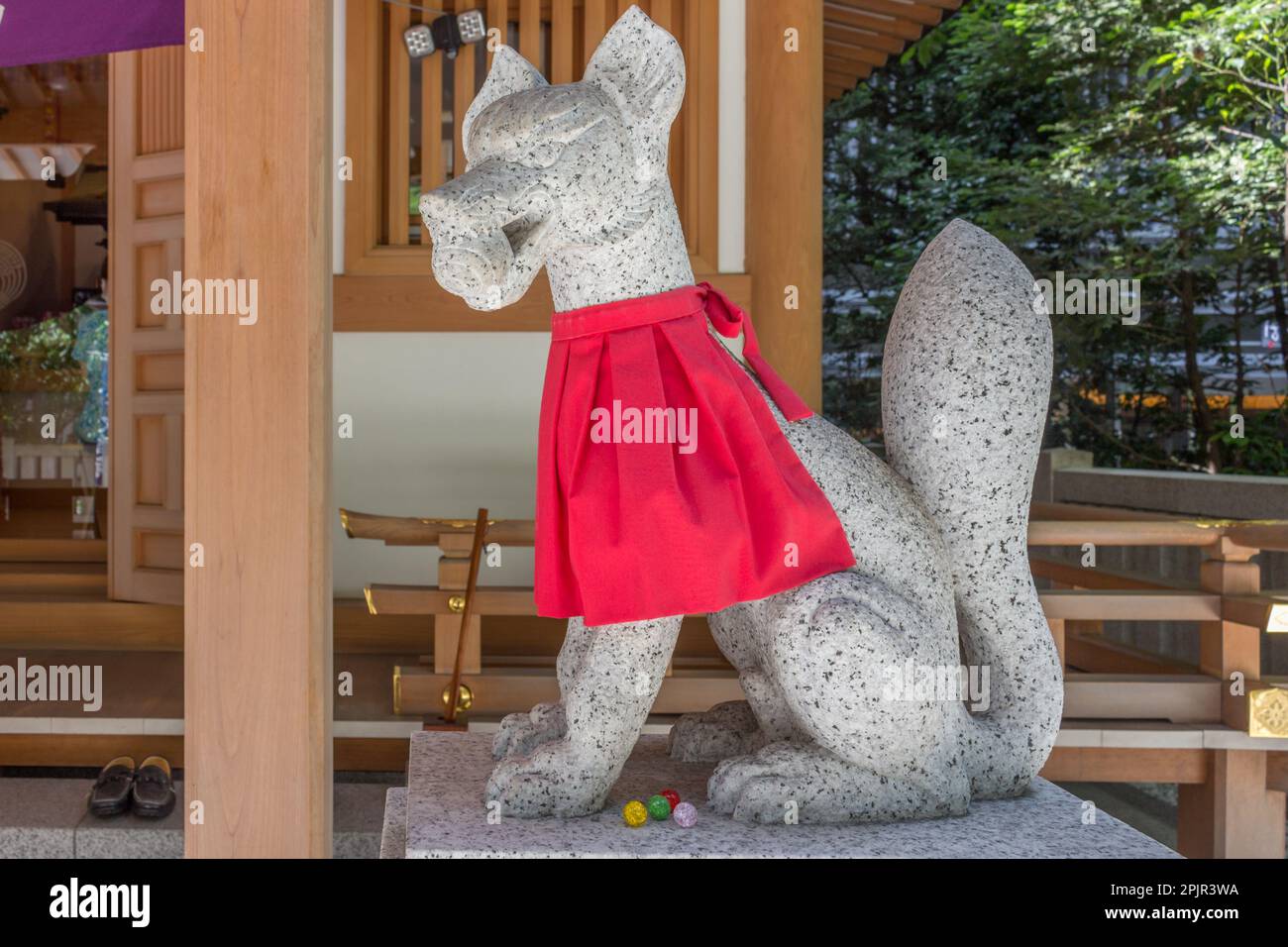 Stone fox, known in Japanese as "kitsune", messenger of the god inari, wearing a red bib ...