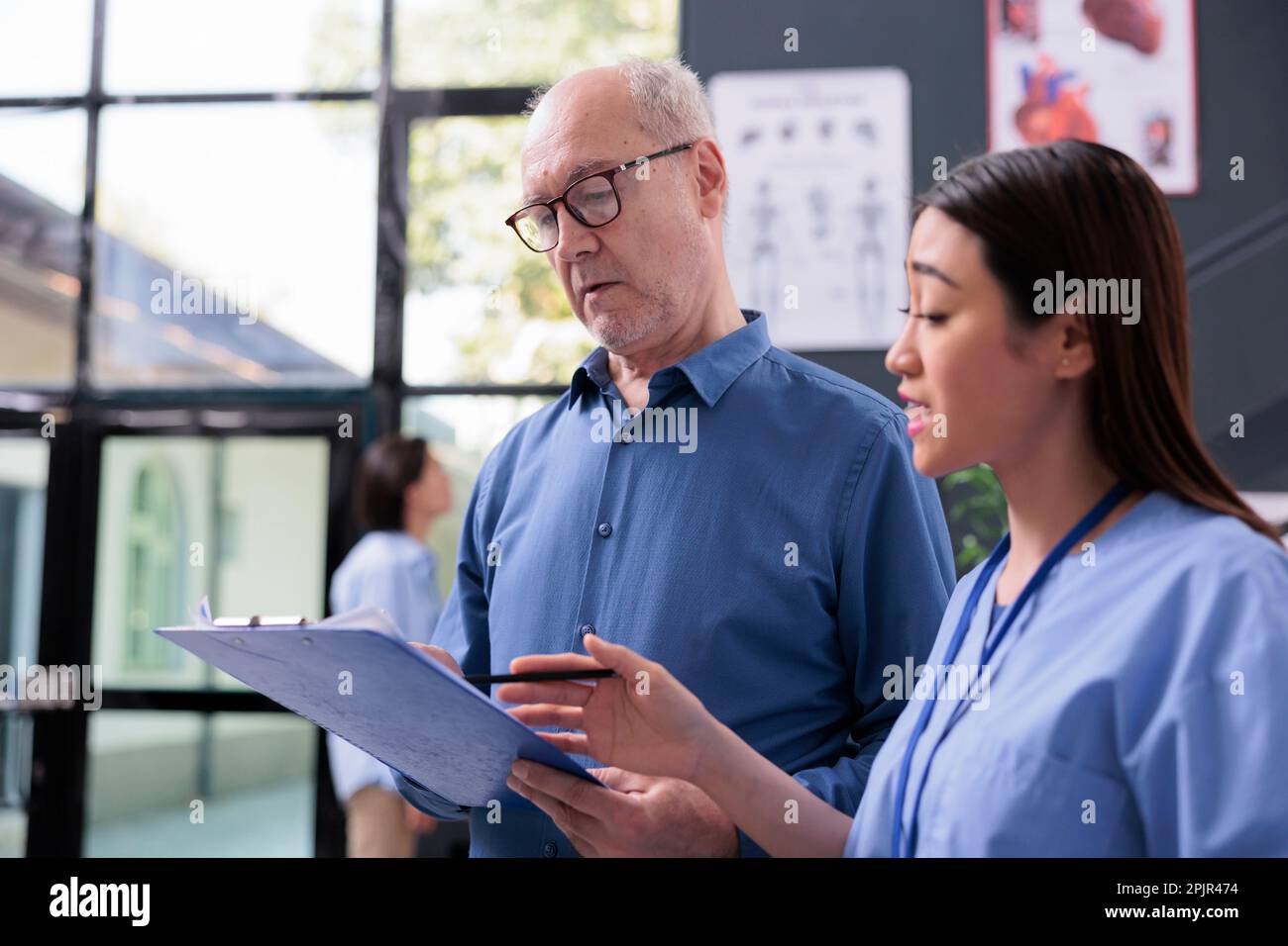 Specialist assistant showing to old patient where need to sign medical ...