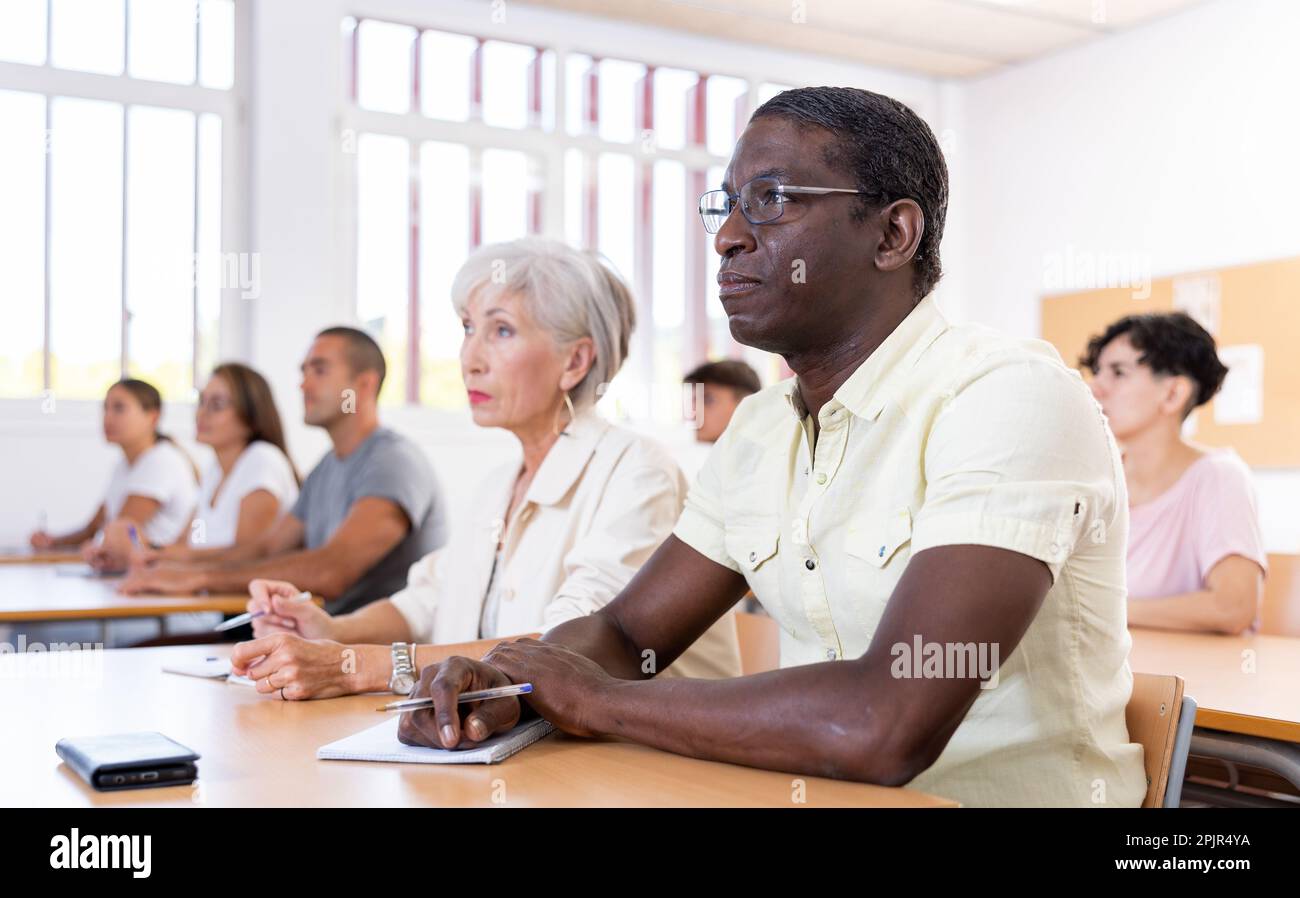 Concentrated african american man listening and taking notes of lecture ...