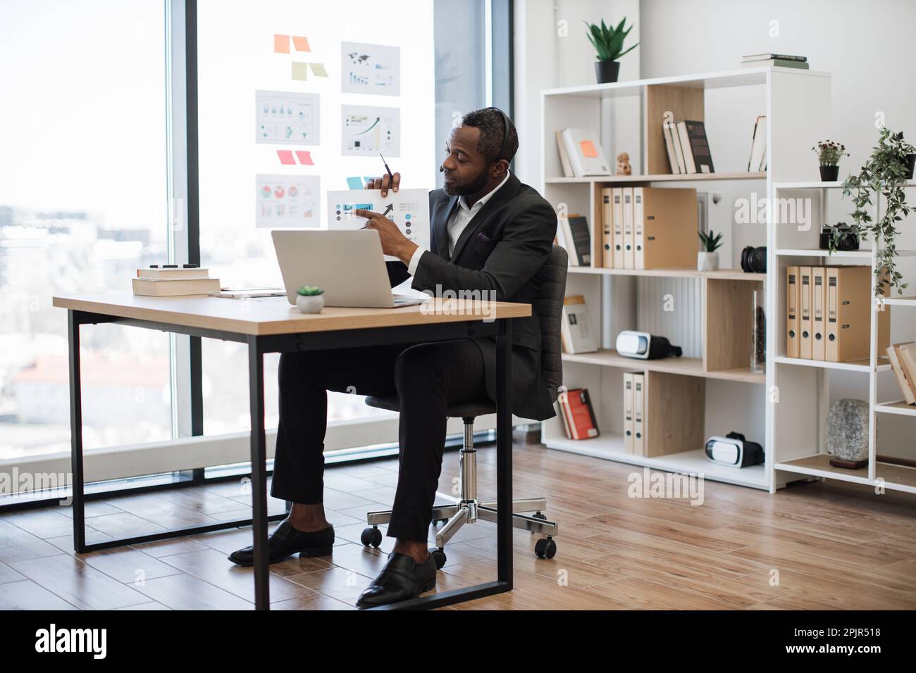 Successful businessman in headset leading online meeting with partners ...