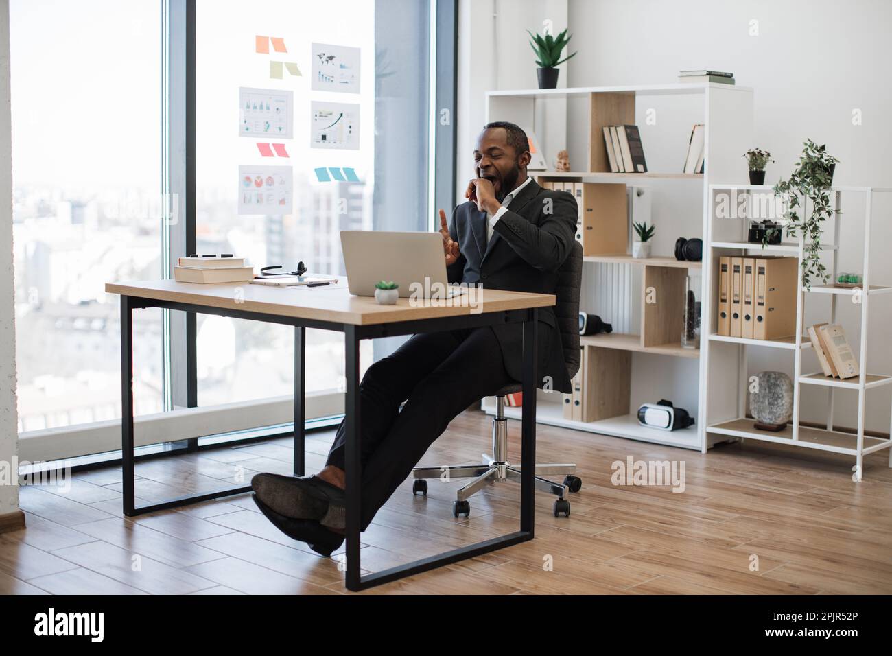 Exhausted african american man in suit sitting at office desk with ...